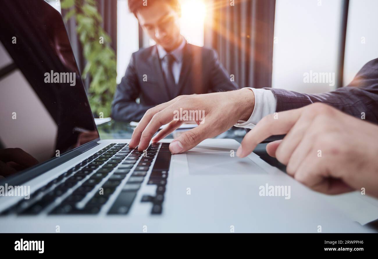 Men's hands are typing on a laptop keyboard against the background of ...