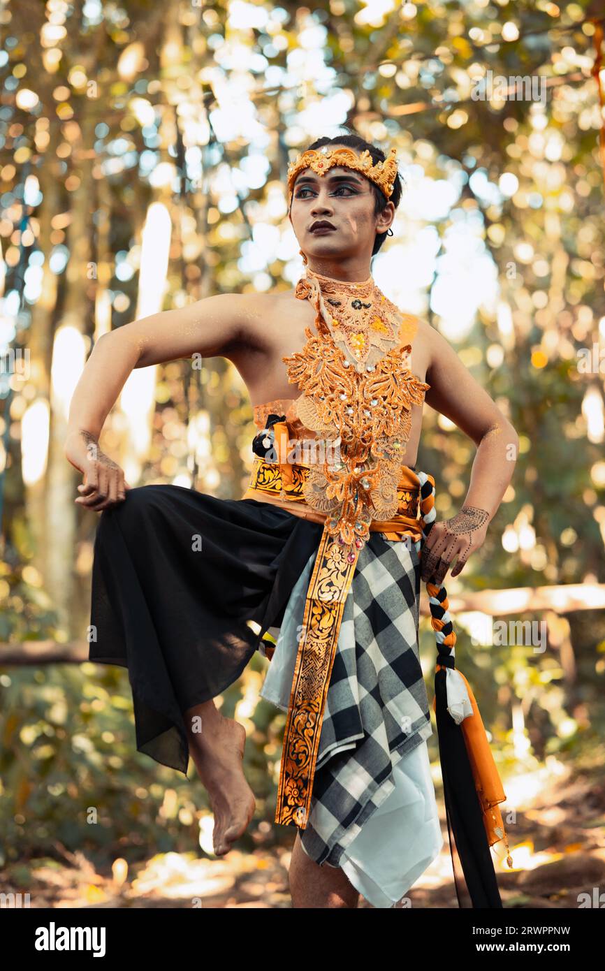 Balinese man raise their feet and dance pose in golden costumes with ...
