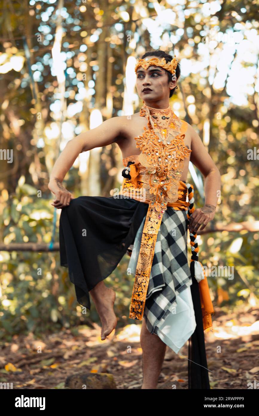 Balinese man raise their feet and dance pose in golden costumes with ...