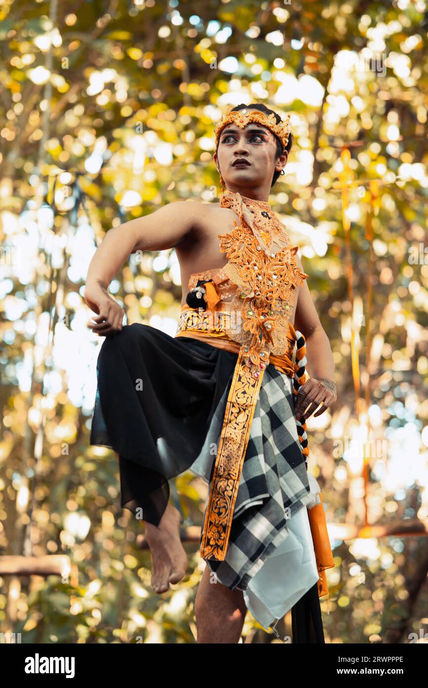 Balinese man raise their feet and dance pose in golden costumes with ...