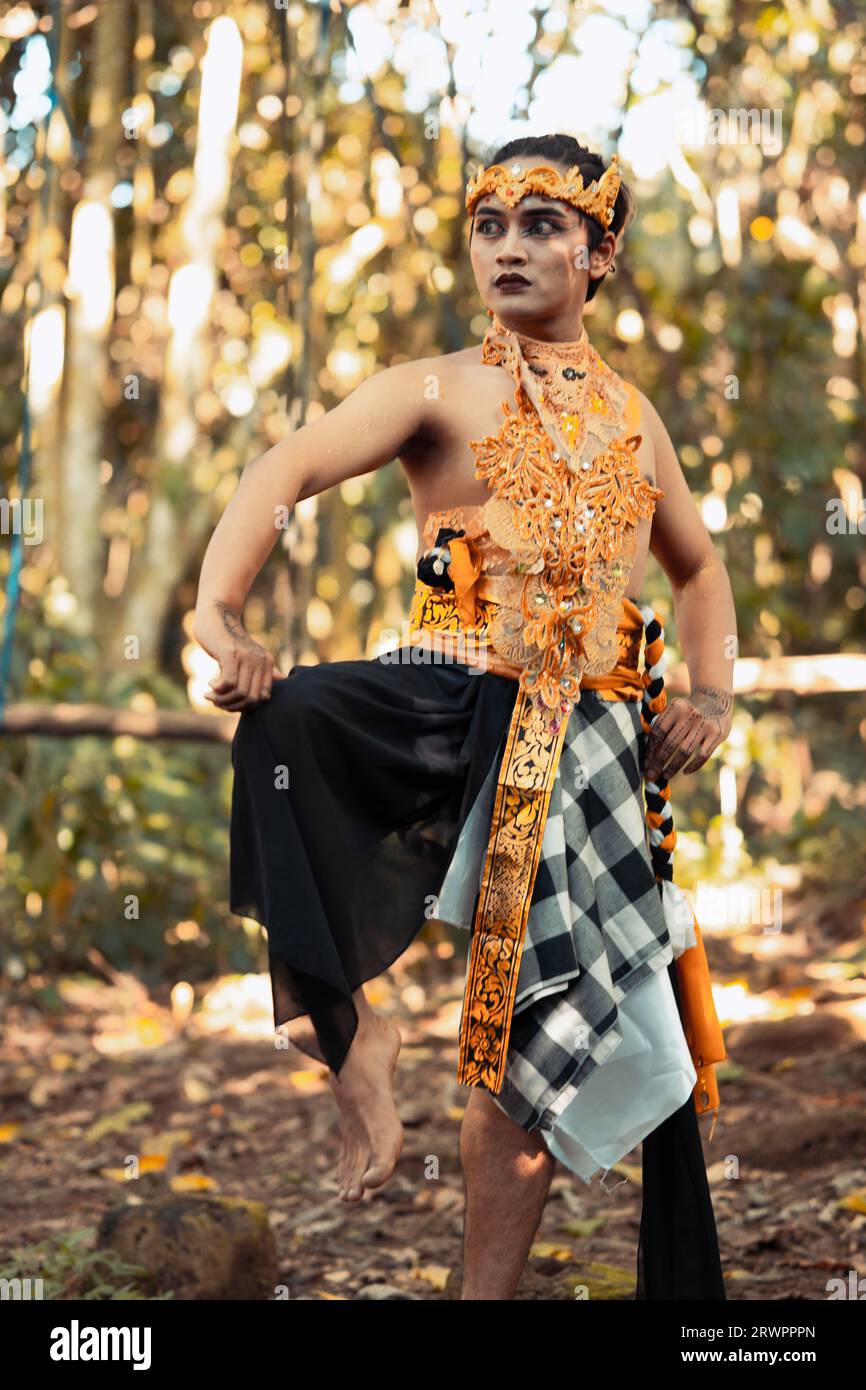 Balinese man raise their feet and dance pose in golden costumes with ...