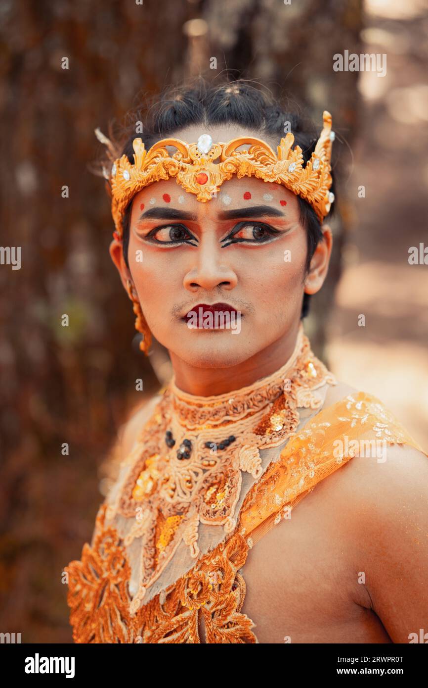 A Manly Asian man poses with a golden crown and gold costume while ...