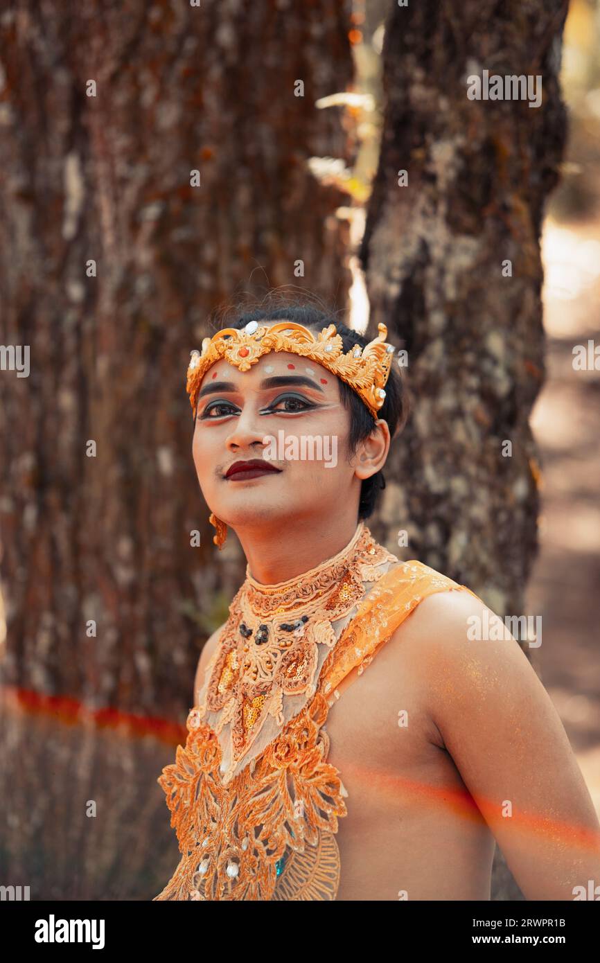 Balinese man standing in the forest while wearing a gold crown and ...
