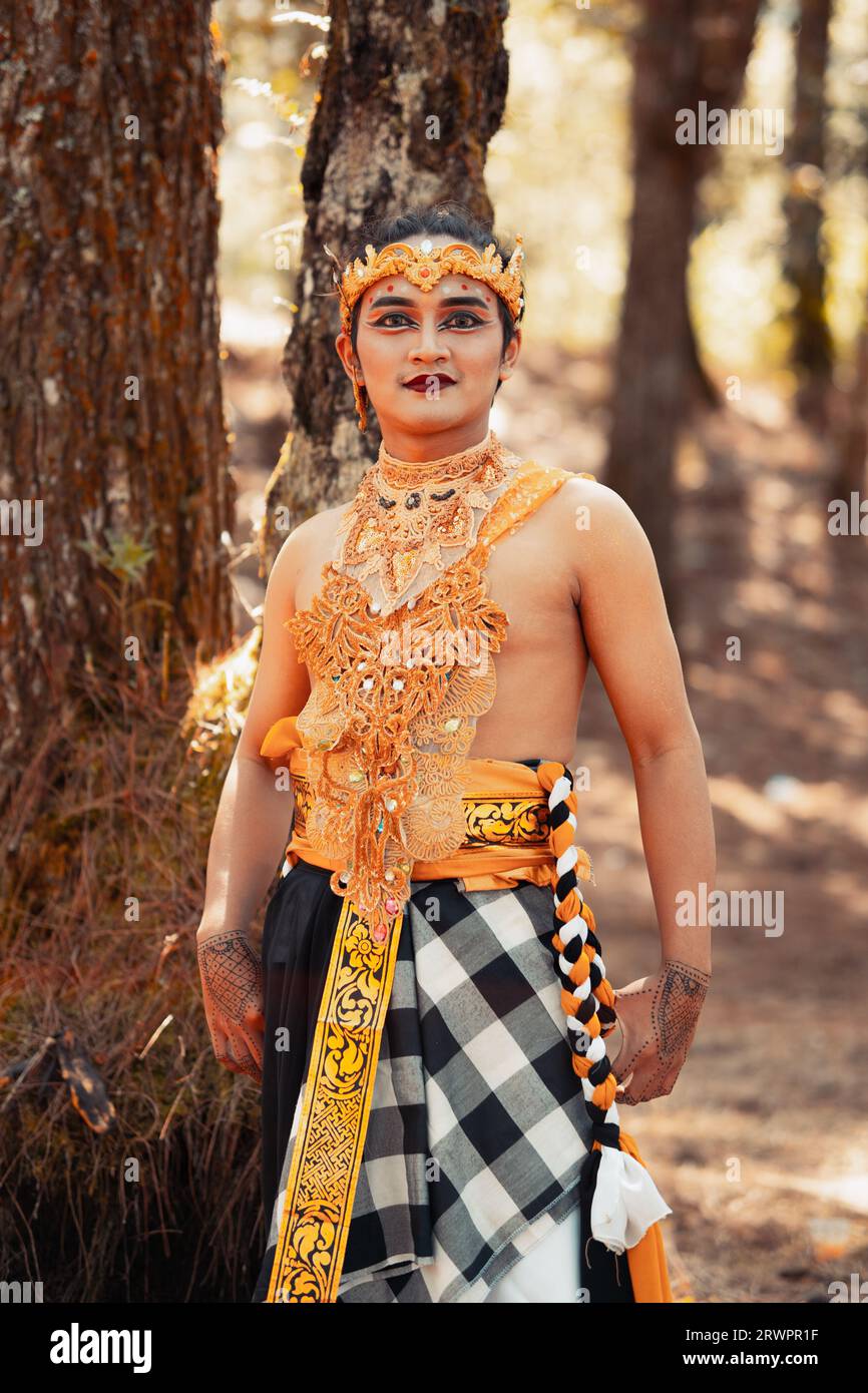 Balinese man standing in the forest while wearing a gold crown and ...