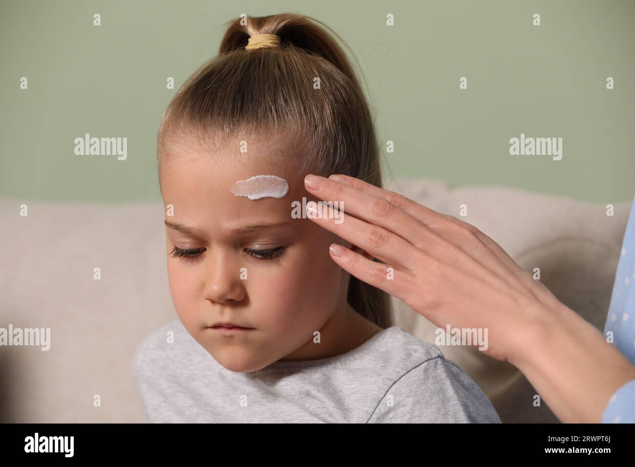 Mother applying ointment onto her daughter's forehead indoors Stock ...