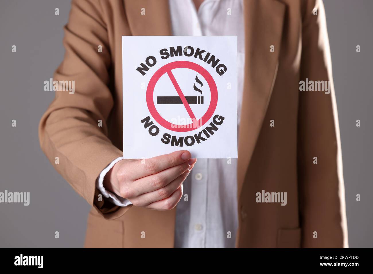 Woman holding card with no smoking sign on gray background, closeup ...