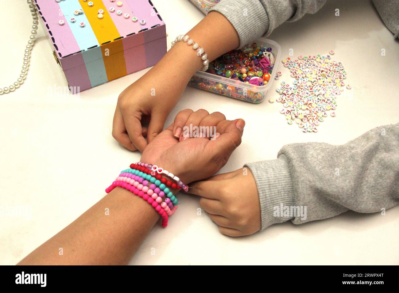 Hands of teenage women make and exchange friendship bracelets as a ...