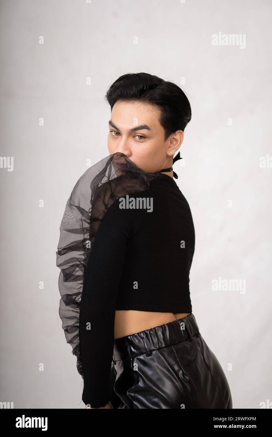 A transgender man poses in a black dress with an elegance face and ...