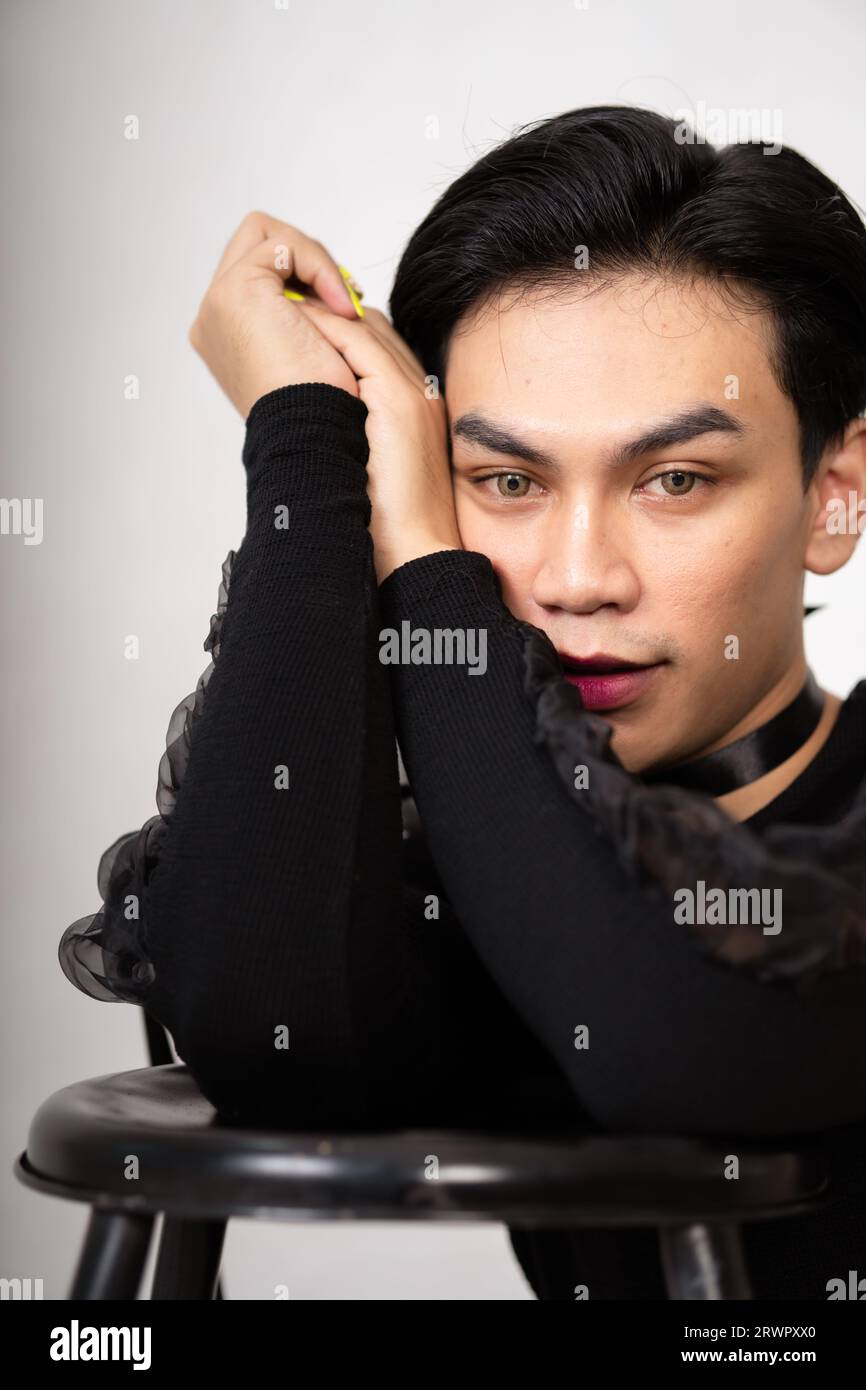 beautiful Asian man posing with the chair while wearing a black costume ...