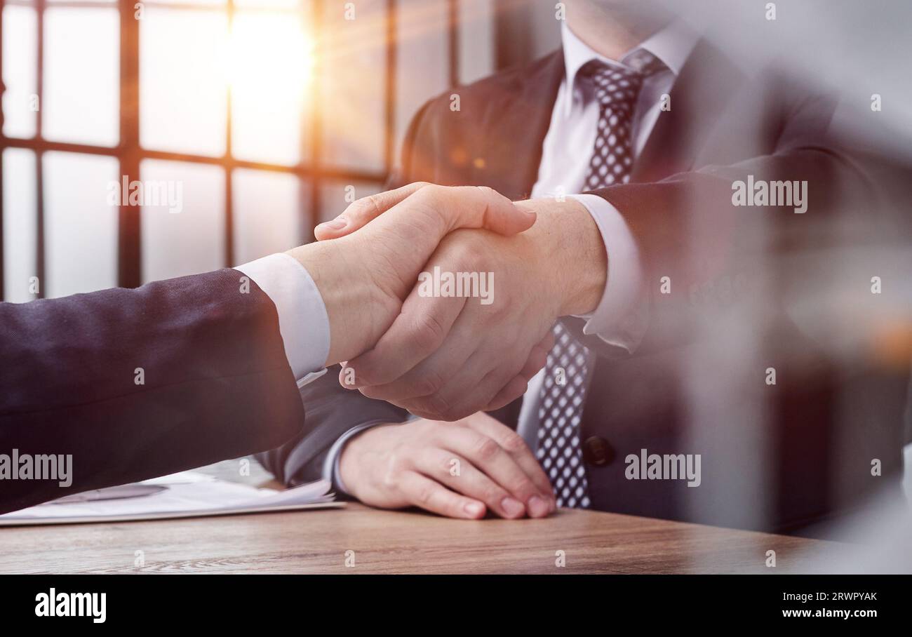 executives shaking hands in front of their manager and a colleague ...