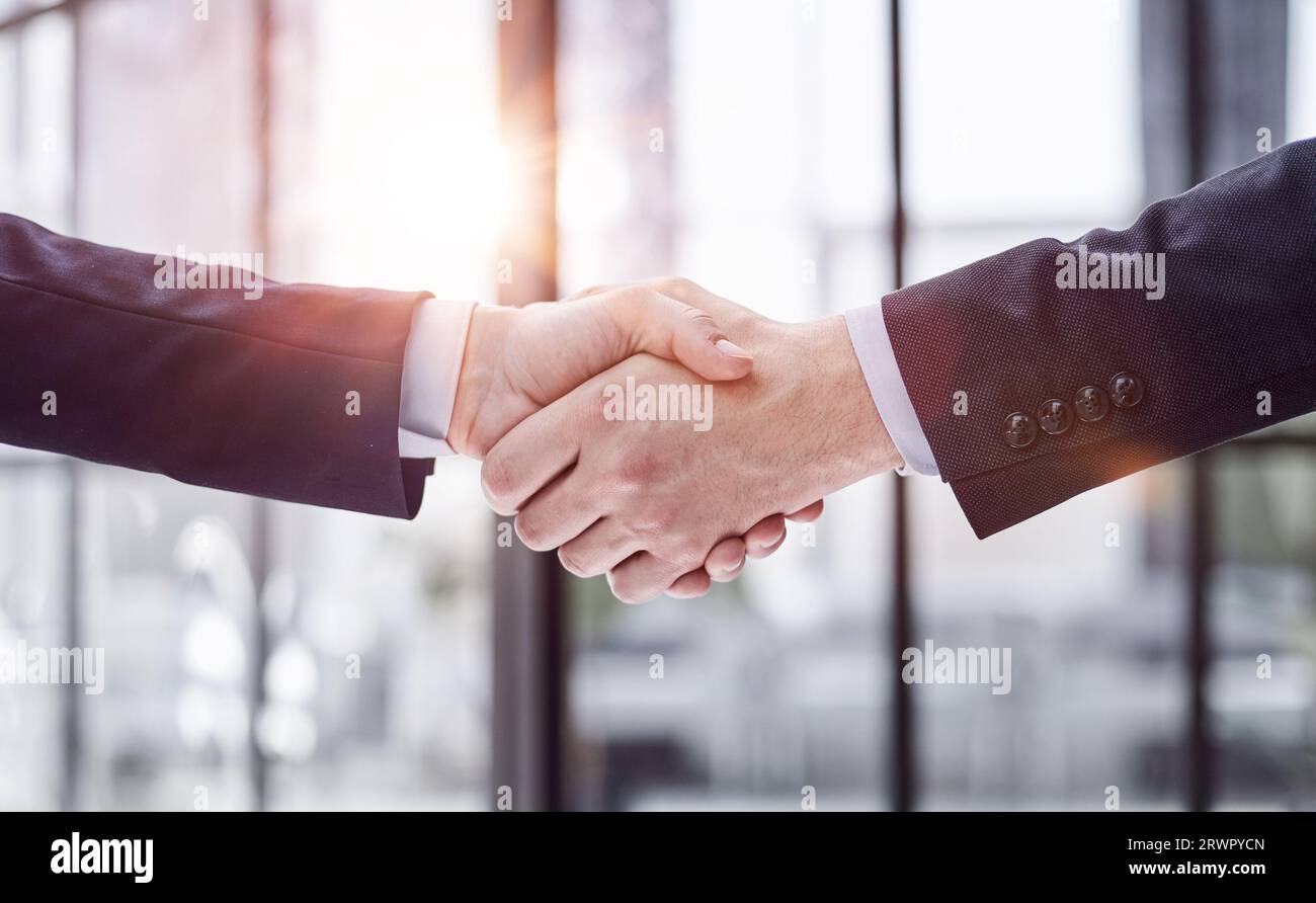 executives shaking hands in front of their manager and a colleague ...