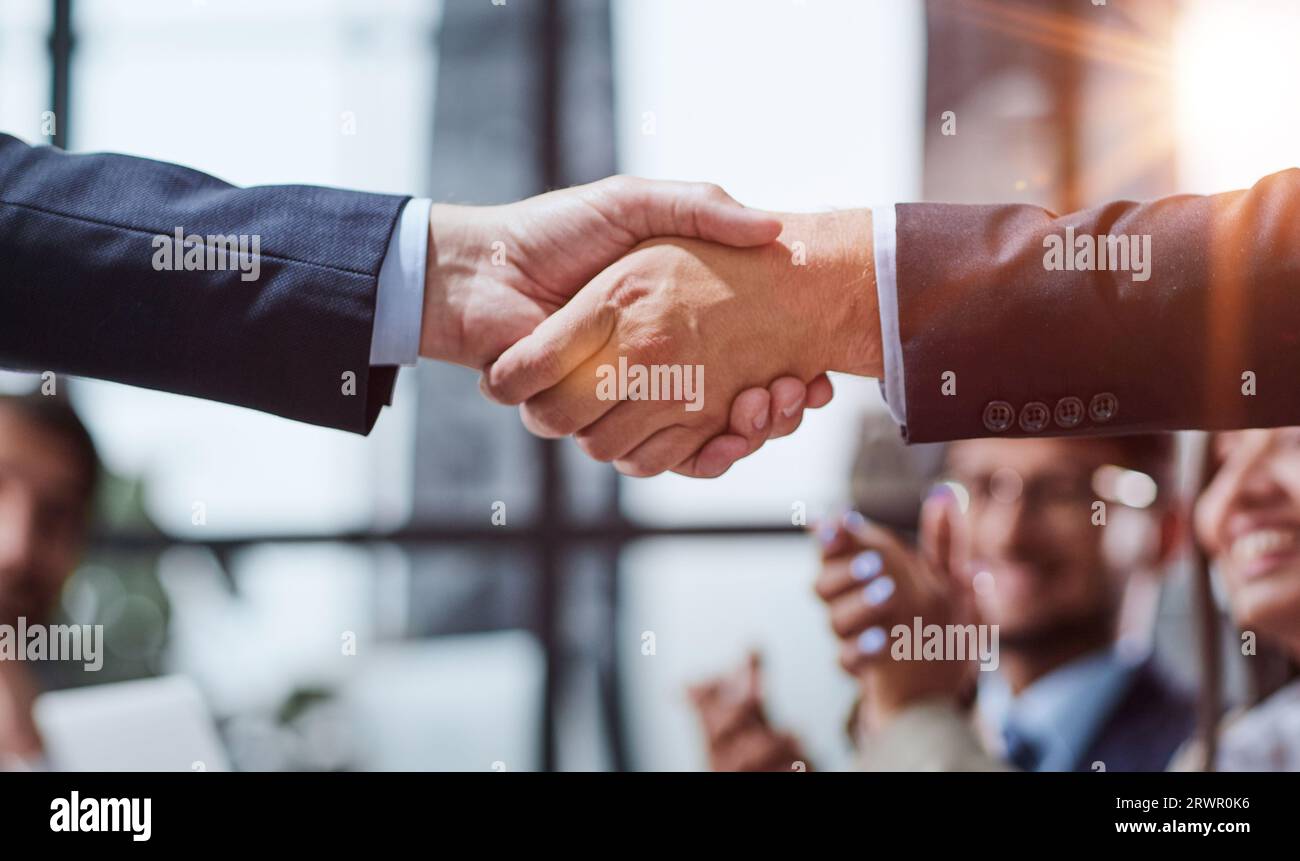Handshake in agreement against young business people in board room ...