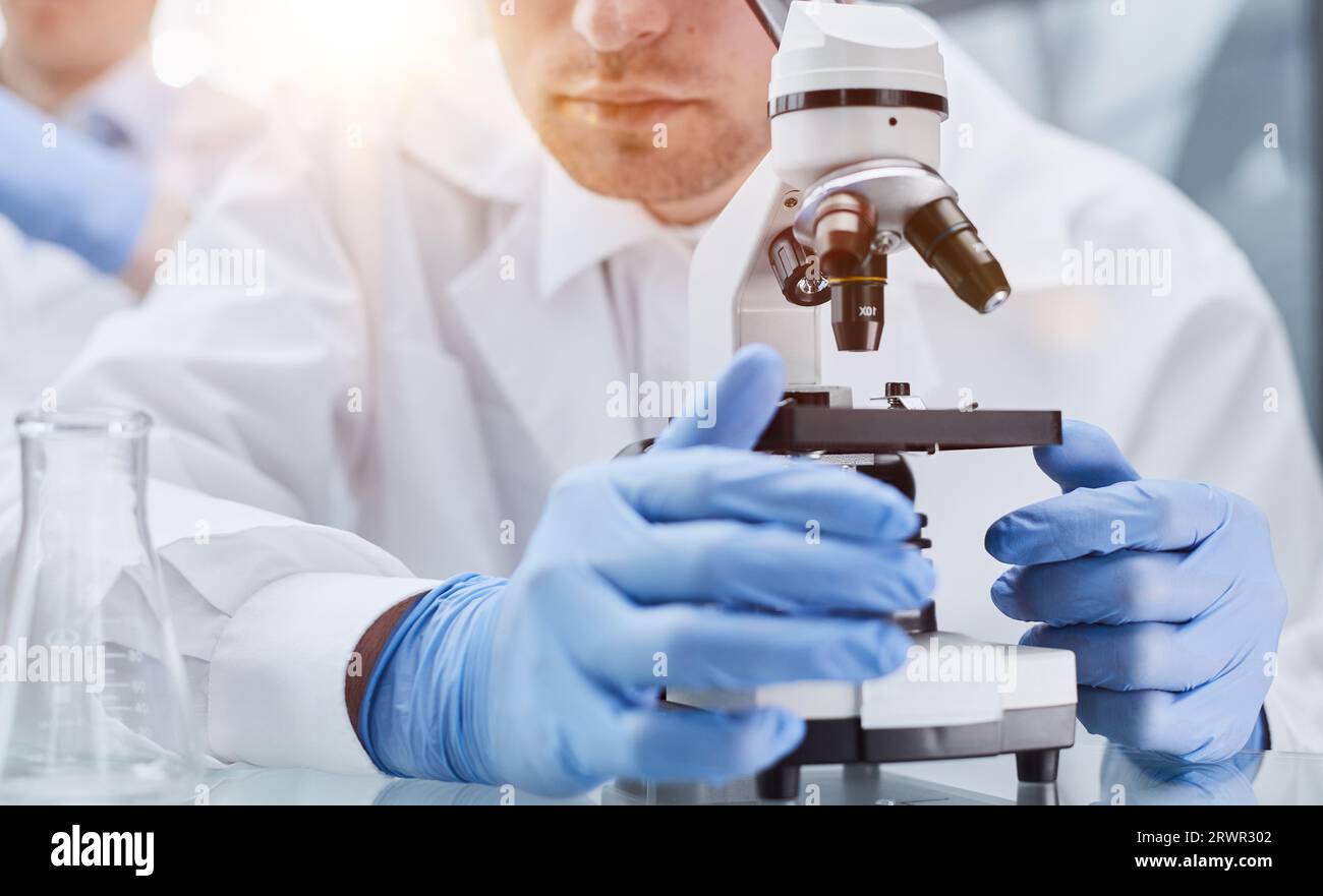 Young scientist looking through a microscope in a laboratory. Young ...