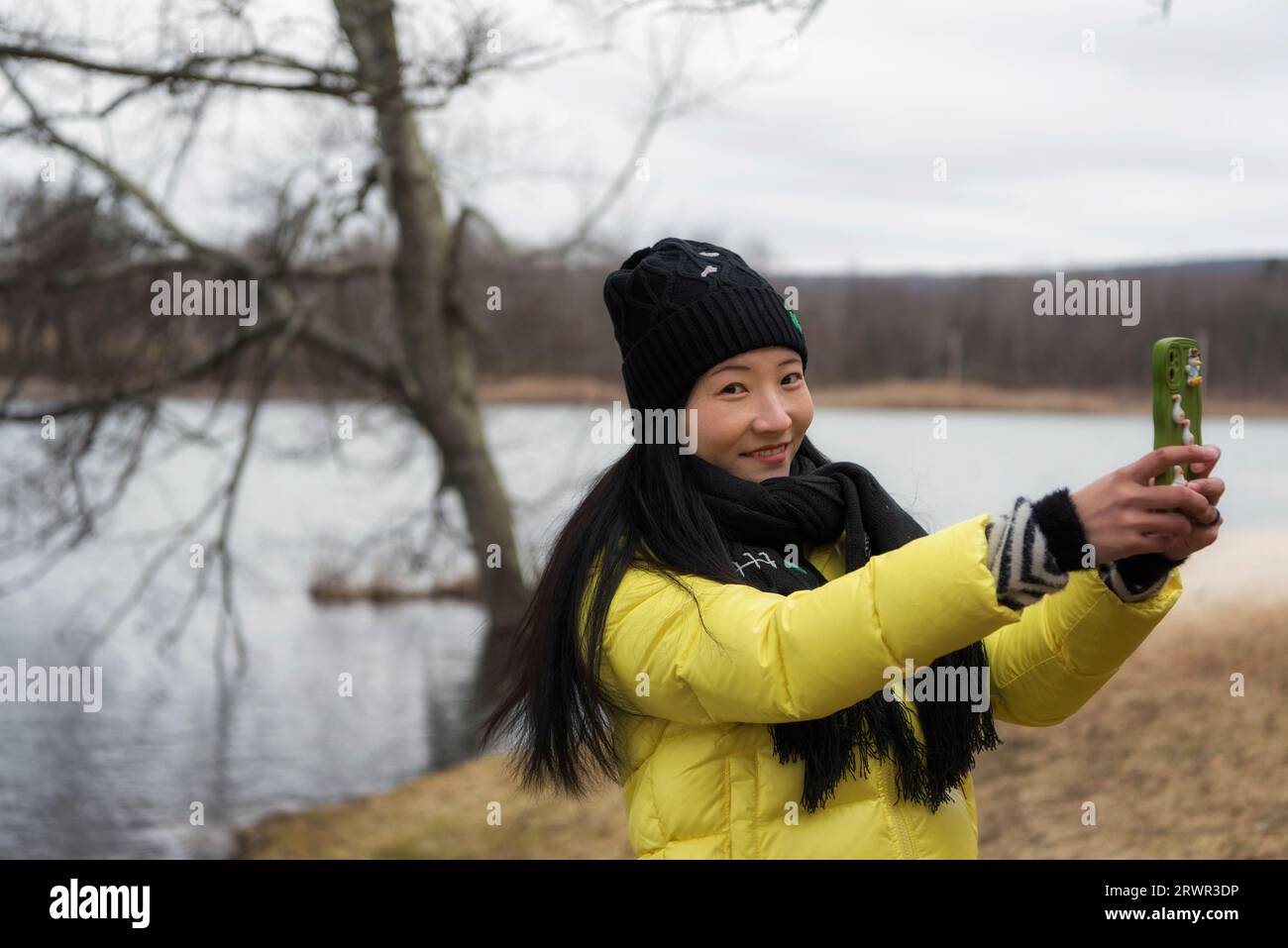 A chinese woman wearing a winter jacket taking a selfie at Rudd Pond ...