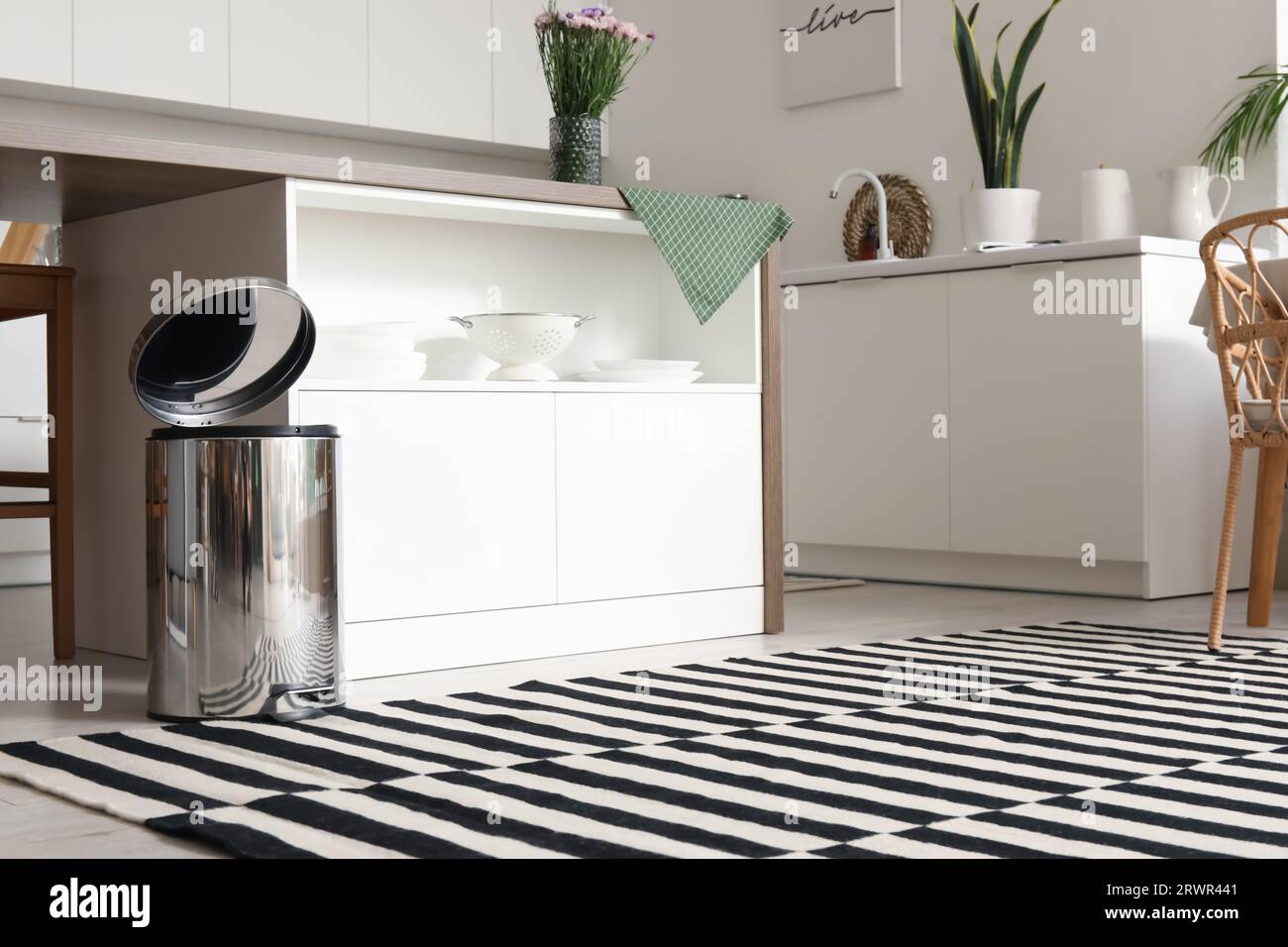 Opened metallic trash bin near table in interior of modern kitchen ...