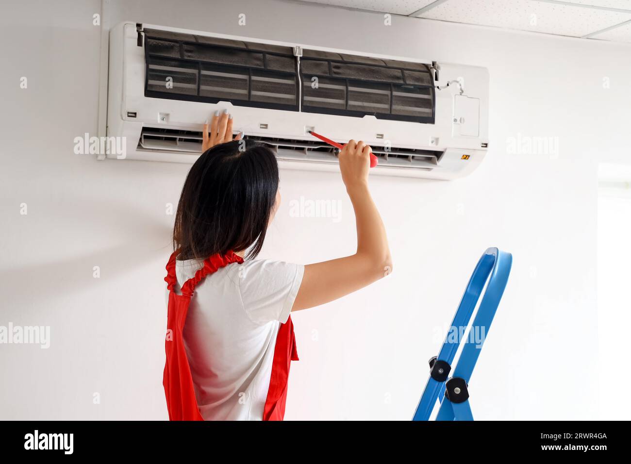Female technician fixing air conditioner in room Stock Photo - Alamy