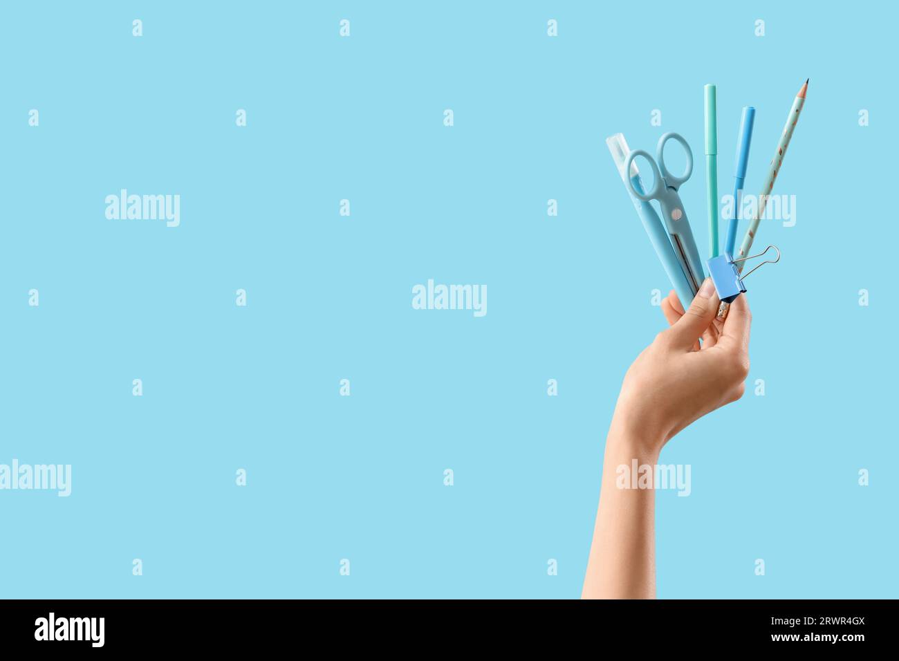 Hand with set of stationery on light blue background Stock Photo - Alamy