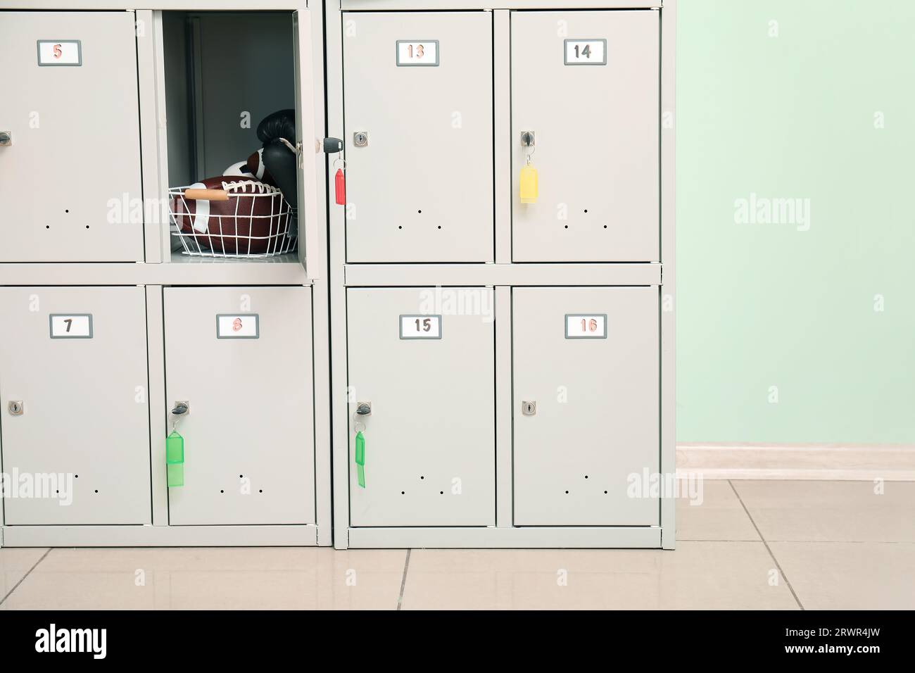 Modern locker with sports equipment near green wall Stock Photo - Alamy