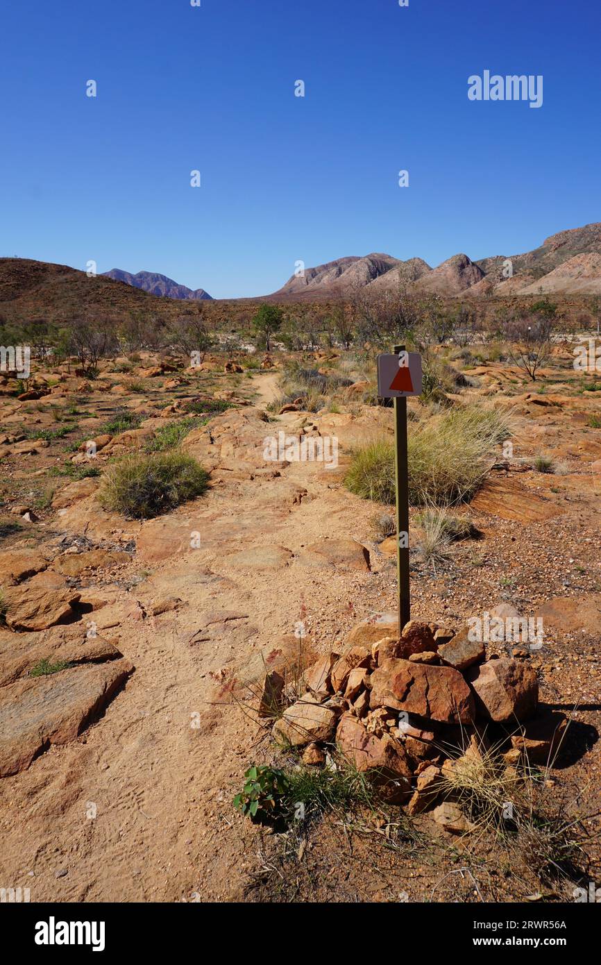 orange directional sign or arrow on a pole on a desert hiking trail in ...