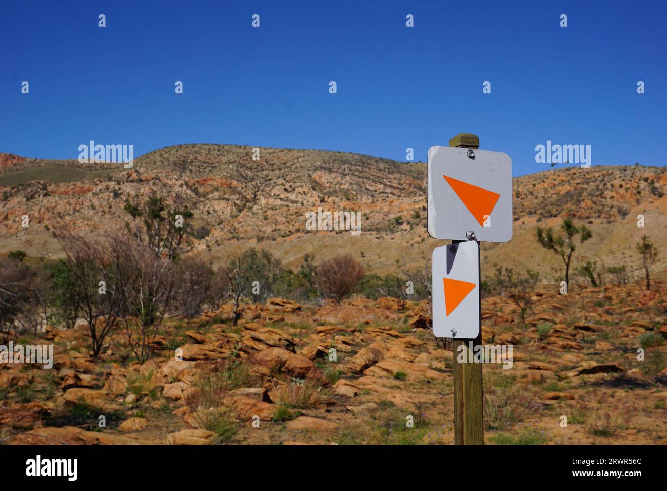 orange directional sign or arrows pointing two directions on a pole on ...