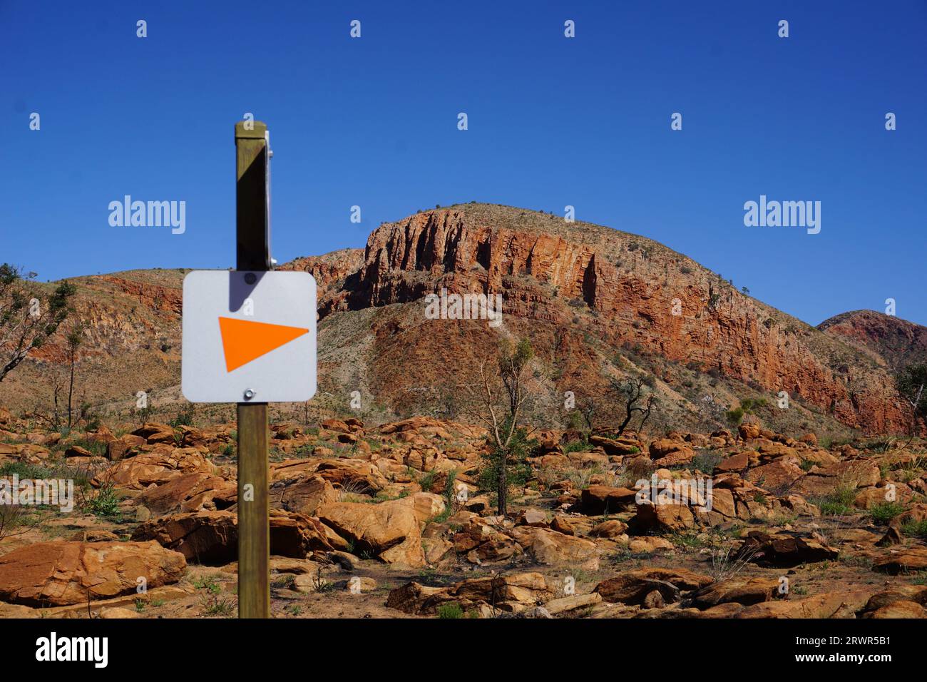 orange directional sign or arrow on a pole on a desert hiking trail in ...
