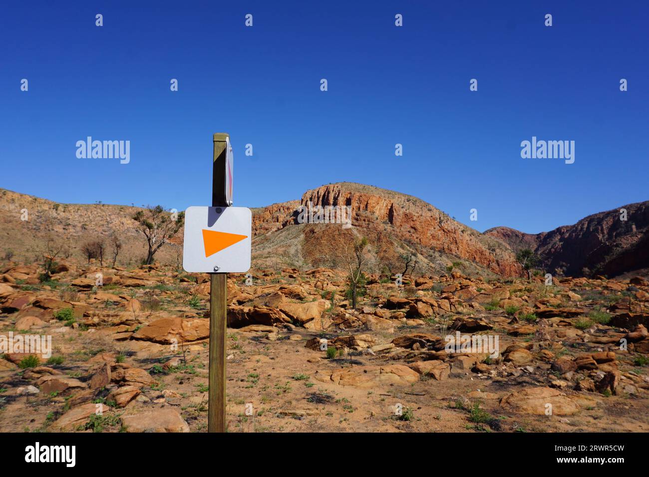 orange directional sign or arrow on a pole on a desert hiking trail in ...