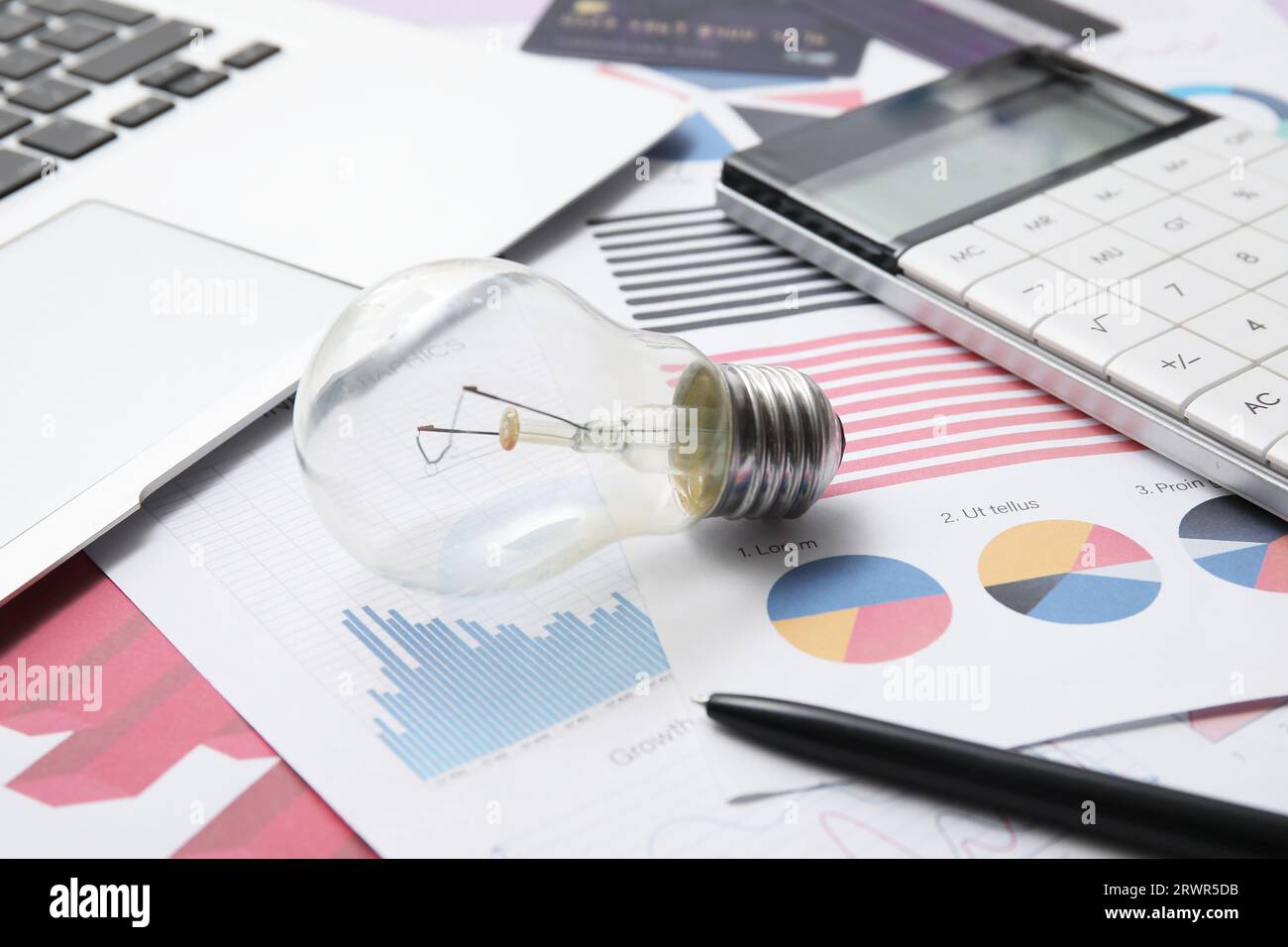 Light bulb, charts and calculator on table, closeup. House rent concept ...