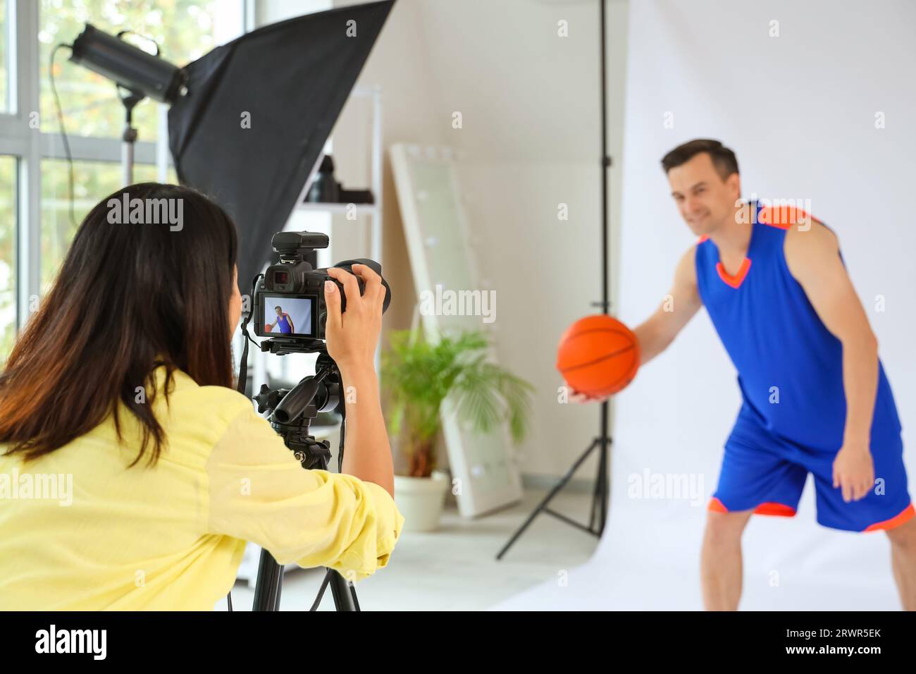 Female photographer taking picture of basketball player in studio Stock ...