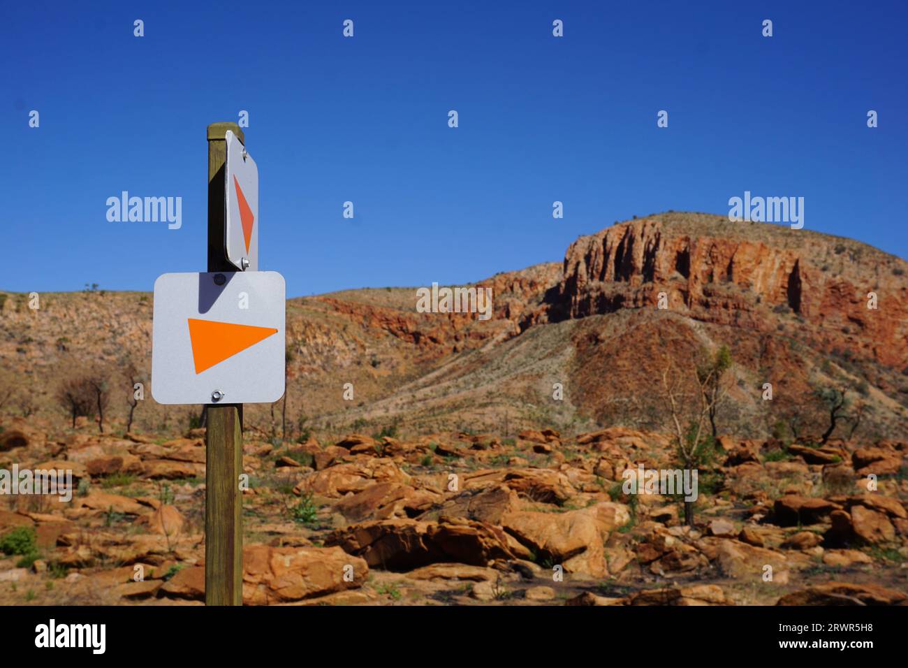 orange directional sign or arrows pointing two directions on a pole on ...