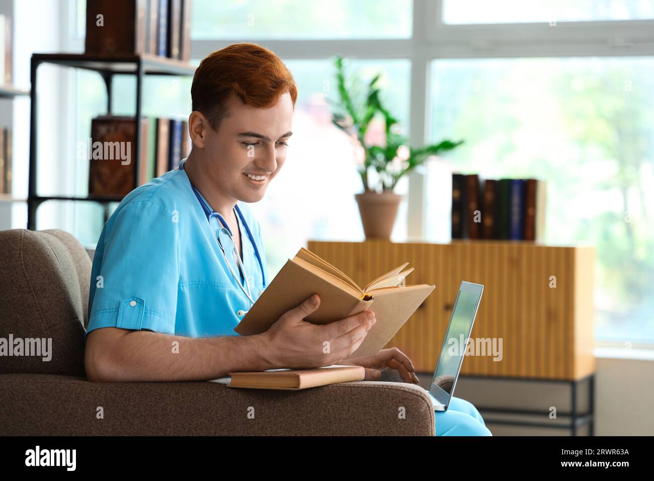 Male medical student studying with laptop in library Stock Photo - Alamy