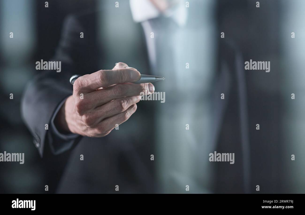 Left hand writing with marker on transparent board on black background ...