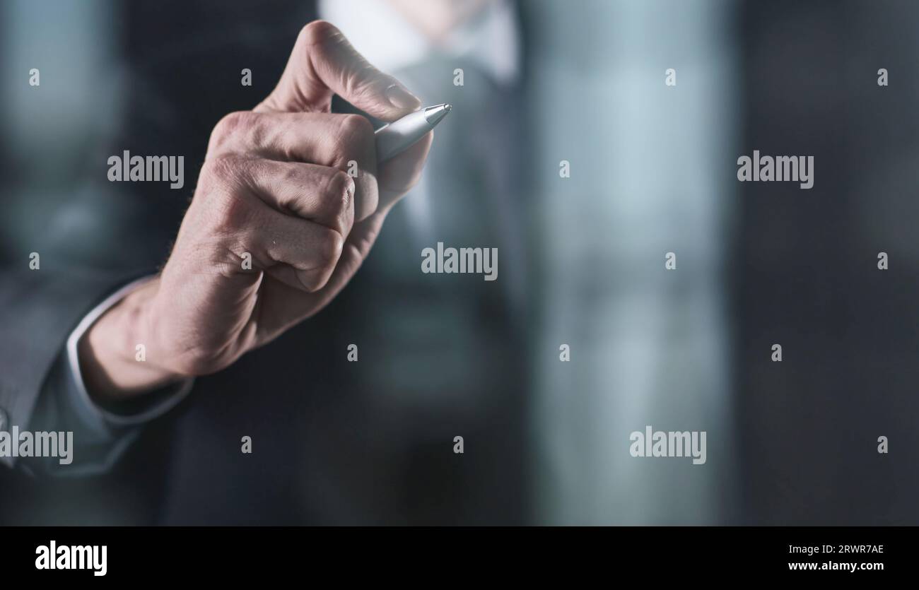 Left hand writing with marker on transparent board on black background ...