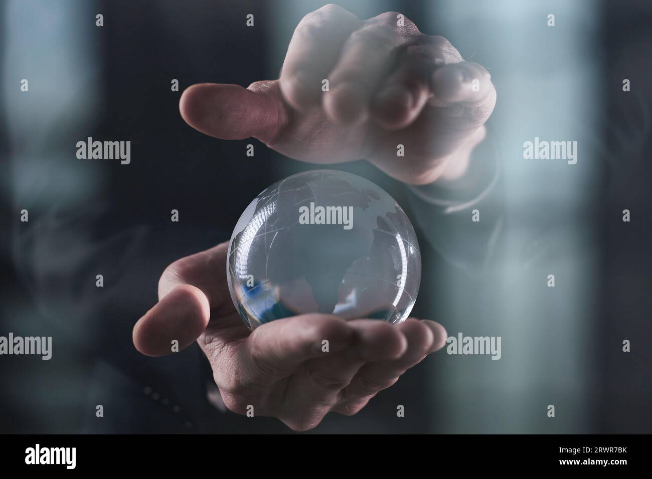 Hands holding a transparent crystal glass ball on a black background ...