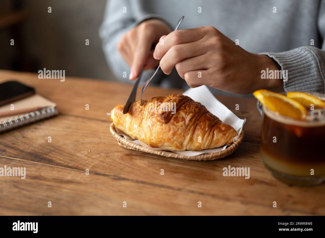 Close-up image of a man cutting a croissant with a fork and knife ...