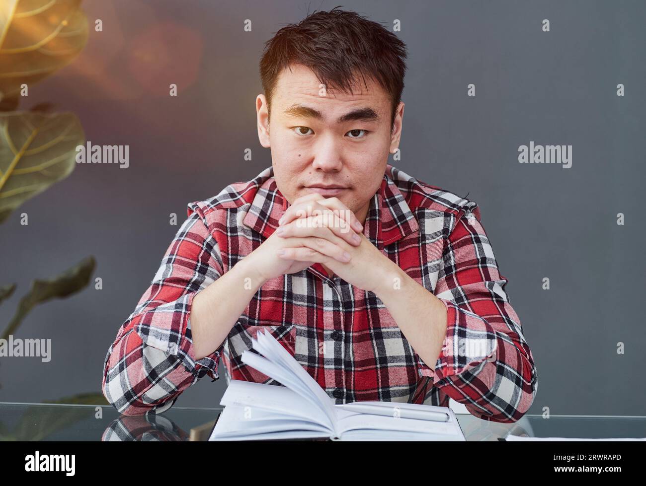 Young Asian man sitting at the table with his chin propped Stock Photo ...