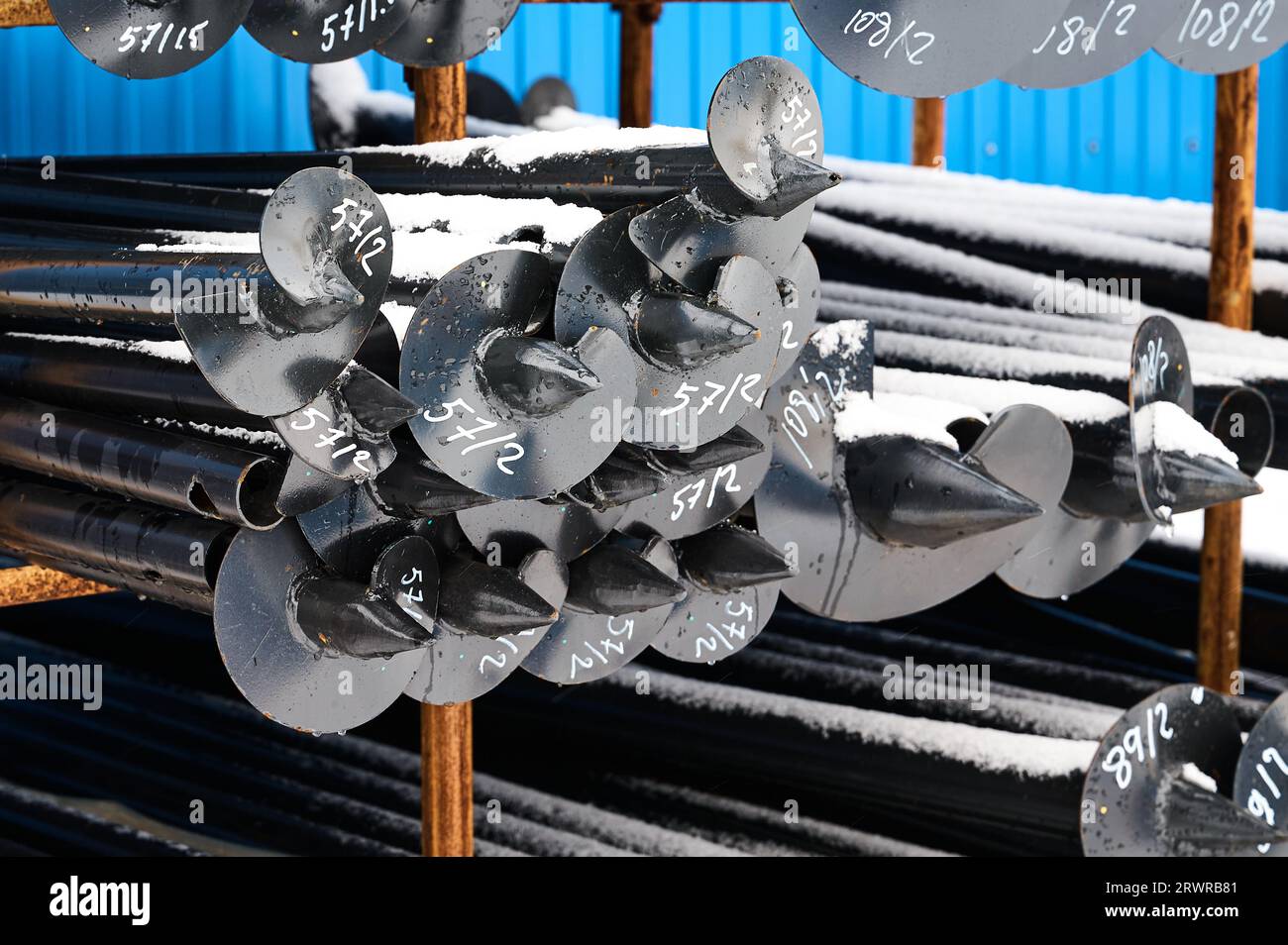 Helical piles on rusty metal rack in snowy warehouse yard Stock Photo ...