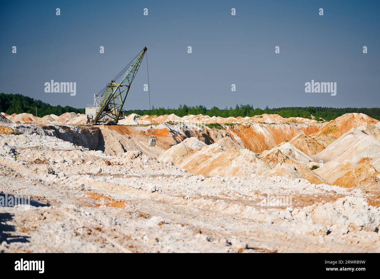 Walking excavator operates in chalk quarry with piles line Stock Photo ...