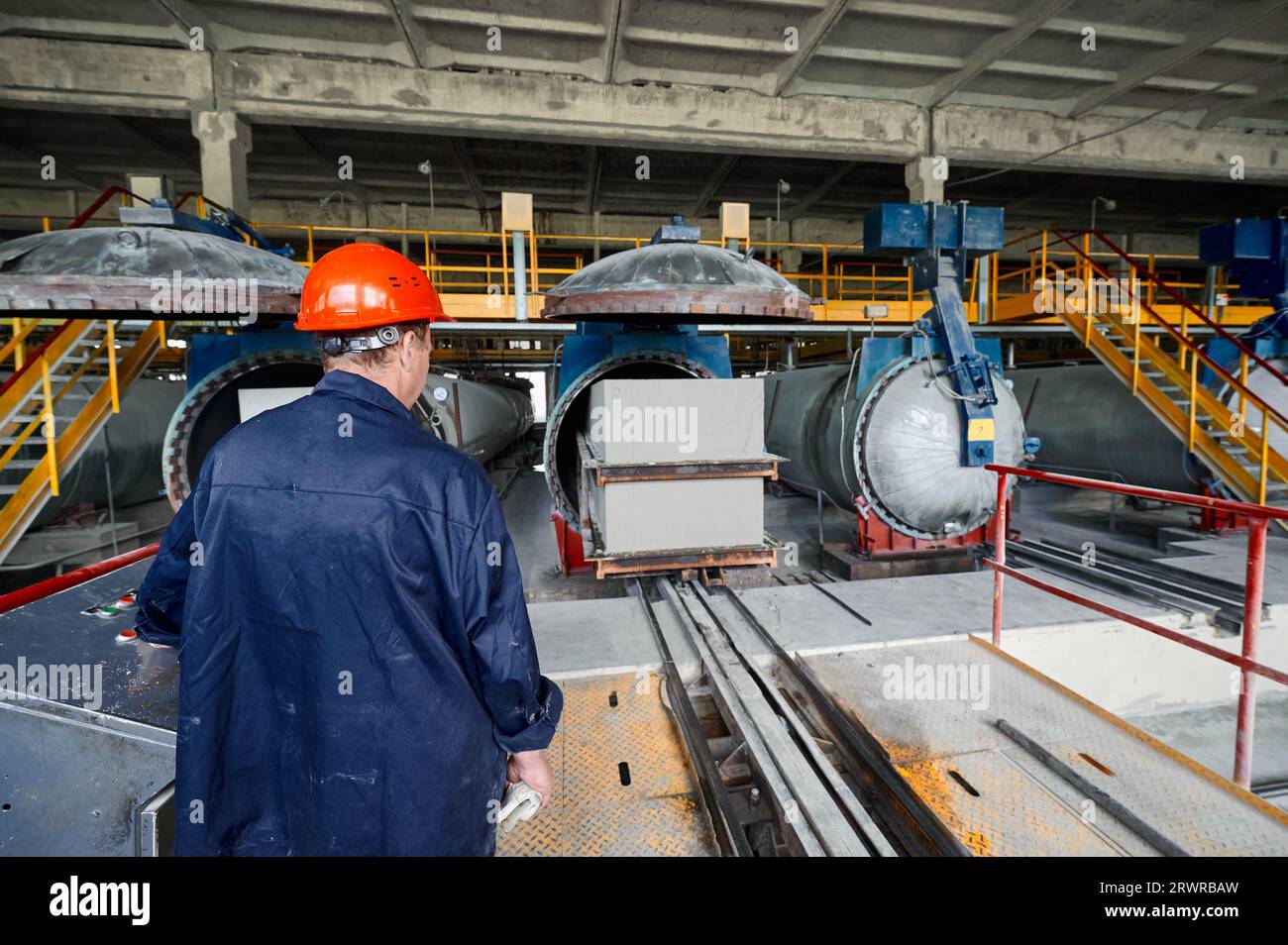 Worker in helmet loads raw blocks into open autoclaves Stock Photo - Alamy