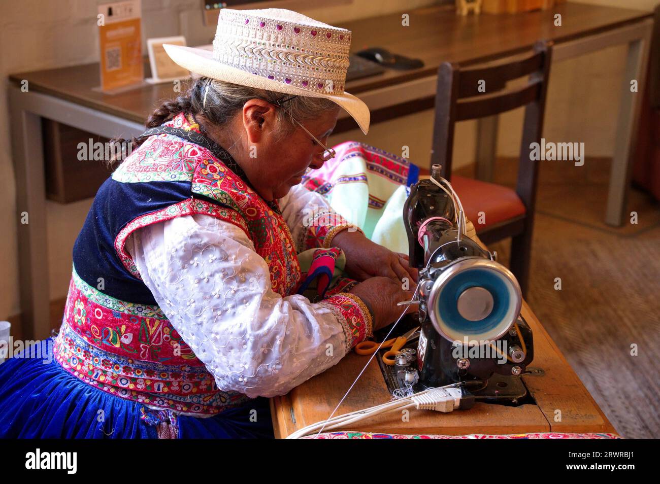 Native woman in traditional clothes sewing on an old sewing machine ...