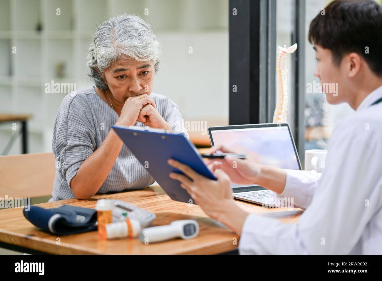 A stressed and serious Asian retired old lady is consulting treatment ...