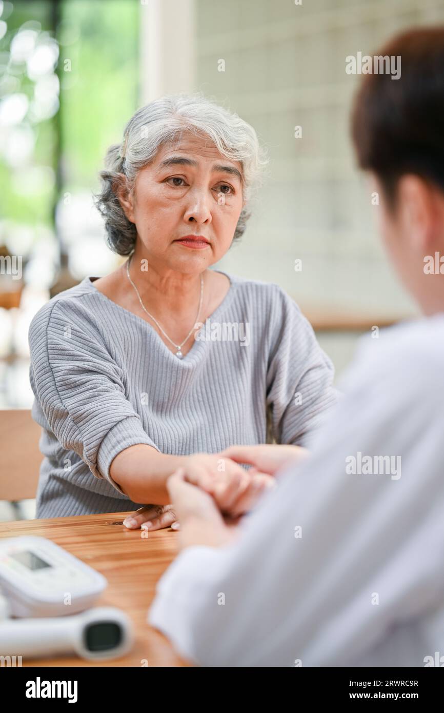 A concerned Asian retired old lady is being diagnosed and checked for ...