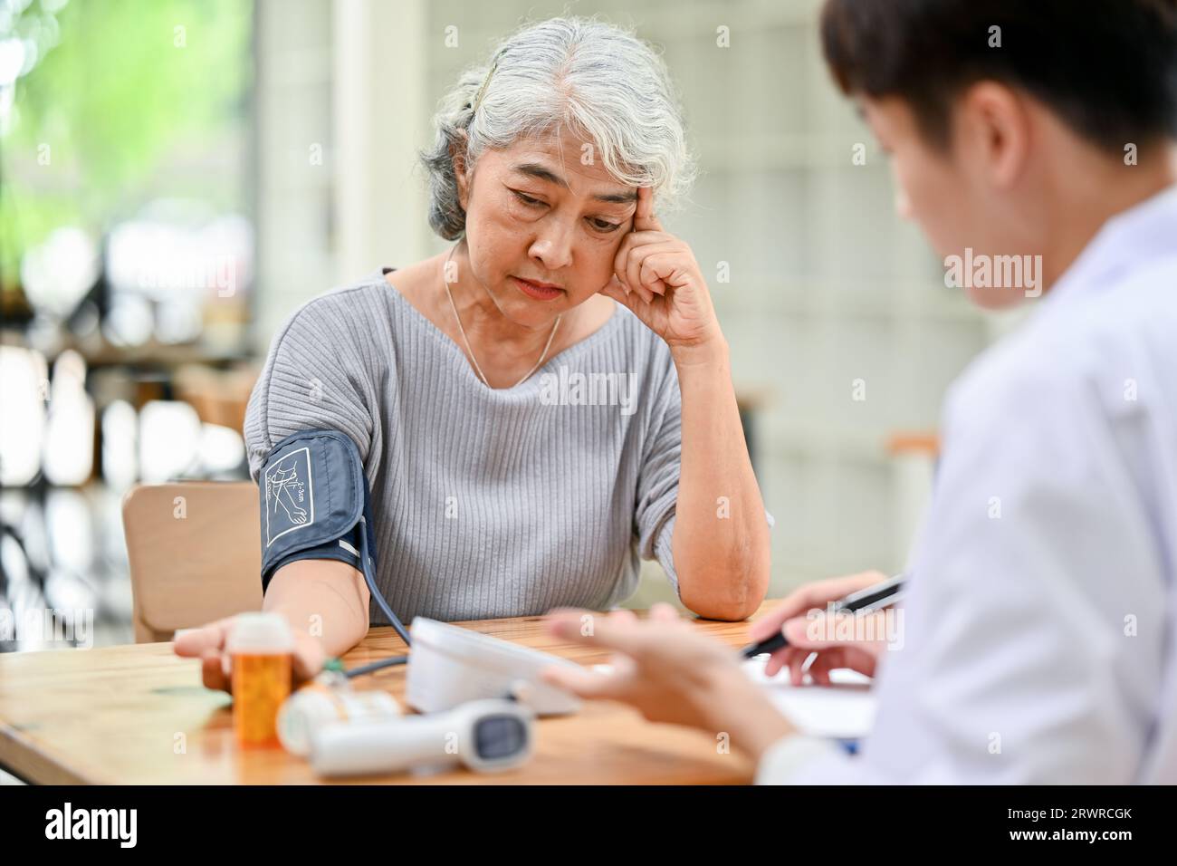 A stressed and concerned Asian retired old lady is being measured for ...