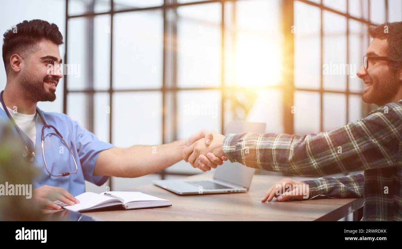 Nice doctor shaking hands with the patient Stock Photo - Alamy