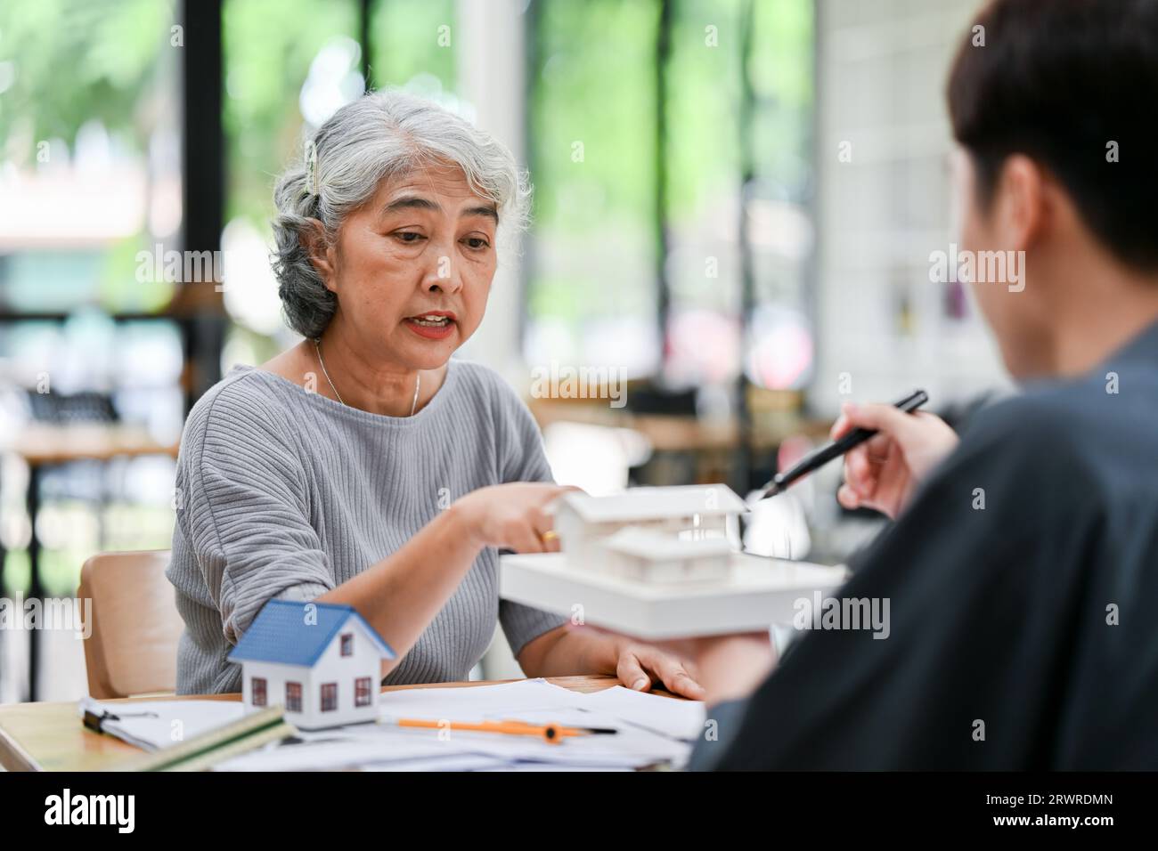 A serious retired Asian lady client is having a serious meeting with ...