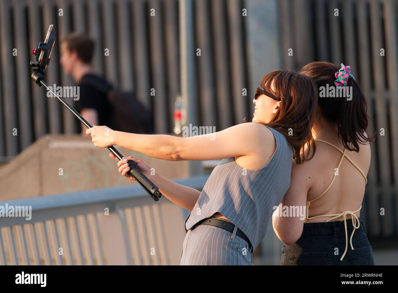 Women using smartphone and selfie stick taking selfies and having fun ...