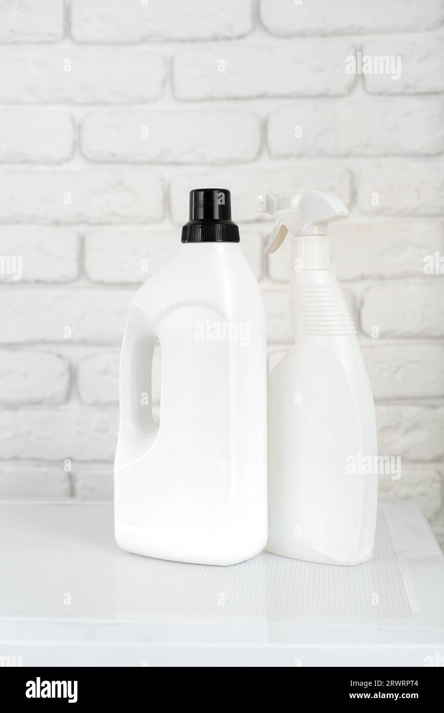 Blank plastic containers of washing gels against white brick background ...