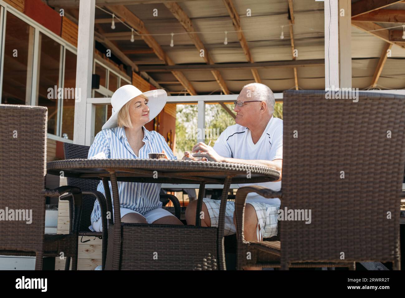 Happy mature middle aged couple talking, woman showing off her hat ...