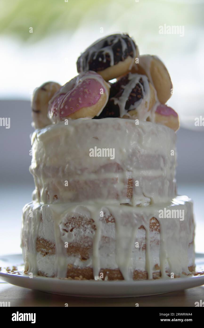 Huge, appetising, tall cake with donuts and melted icing for a ...
