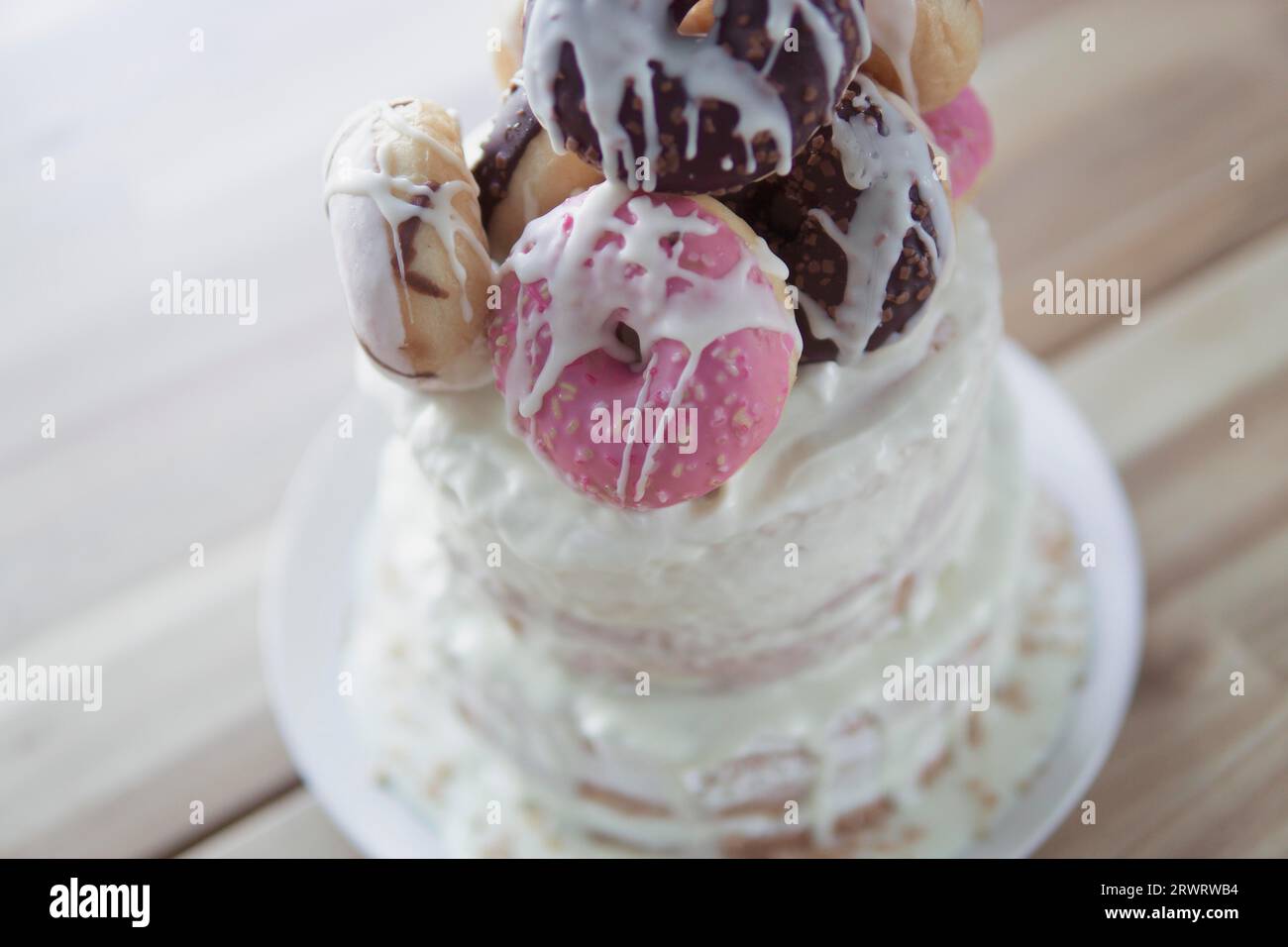 Huge, appetising, tall cake with donuts and melted icing for a ...