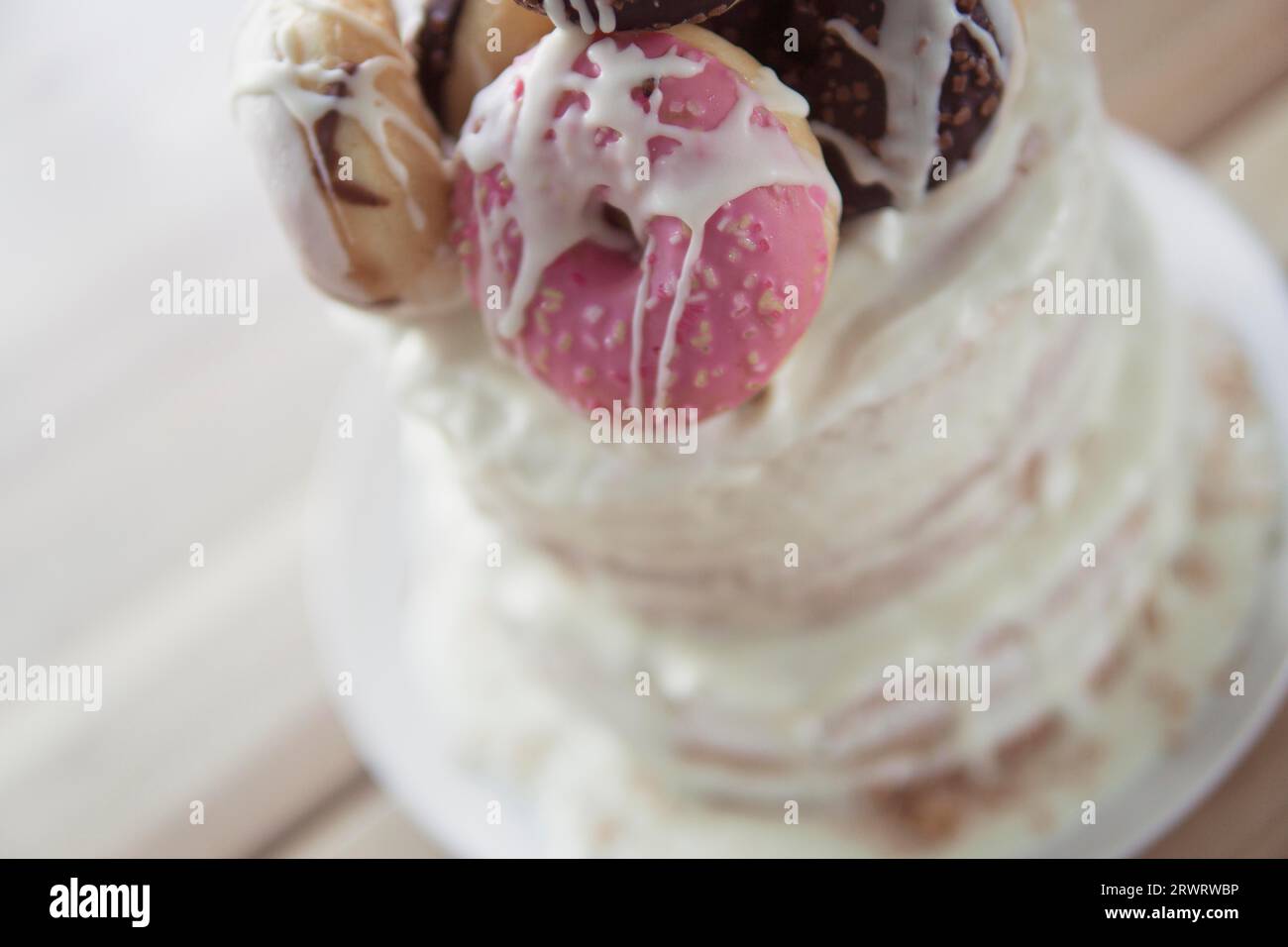 Huge, appetising, tall cake with donuts and melted icing for a ...